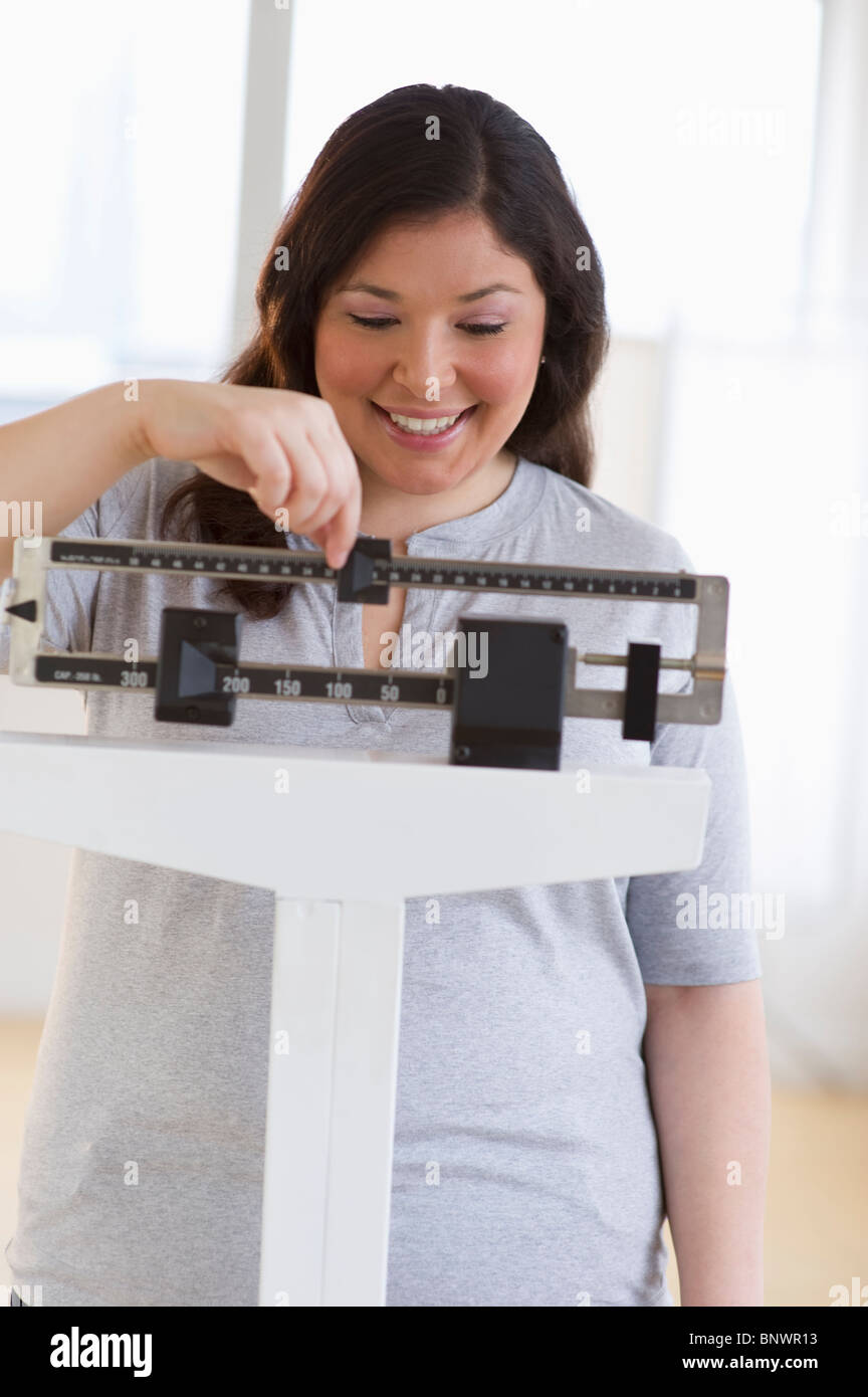 Happy woman standing on scale Stock Photo - Alamy