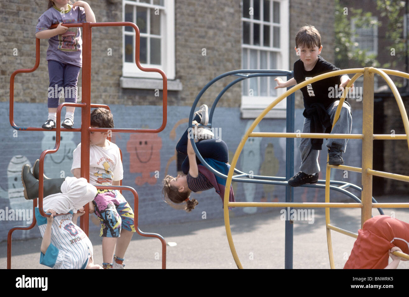 primary school children playing on a climbing frame in the playground ...
