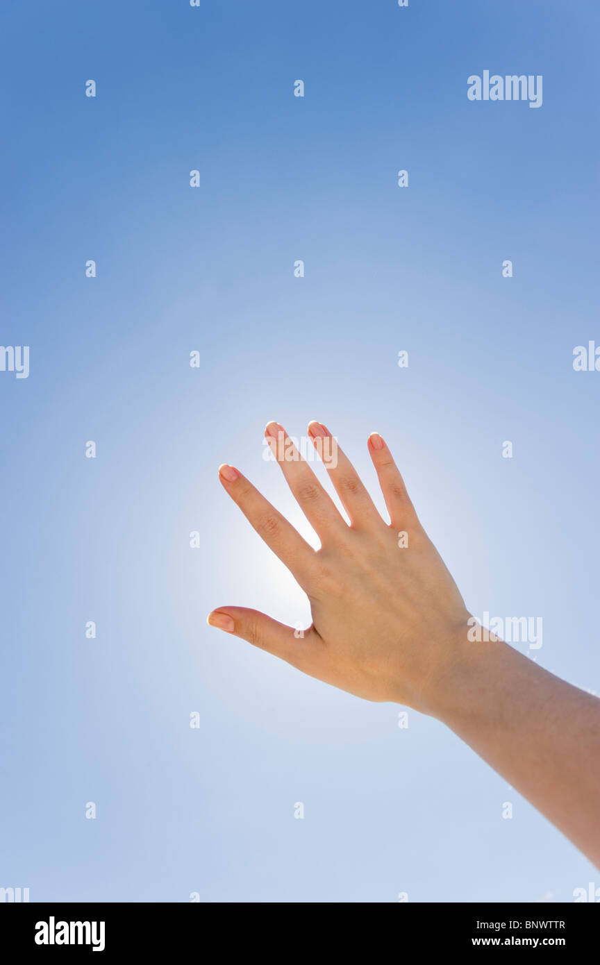 Hand held up in front of sunshine Stock Photo - Alamy