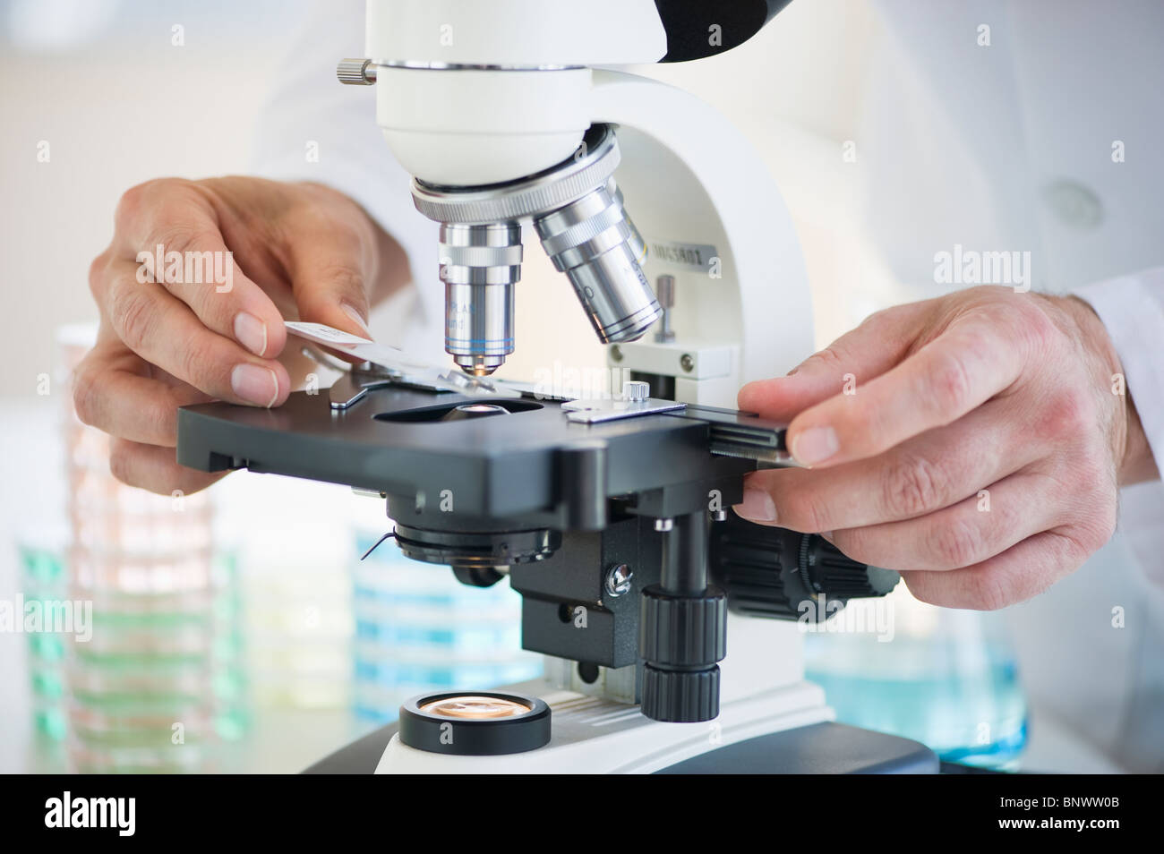 Hands on a microscope Stock Photo - Alamy