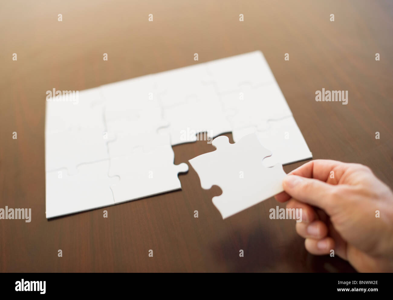 Hand putting last puzzle piece in puzzle Stock Photo - Alamy