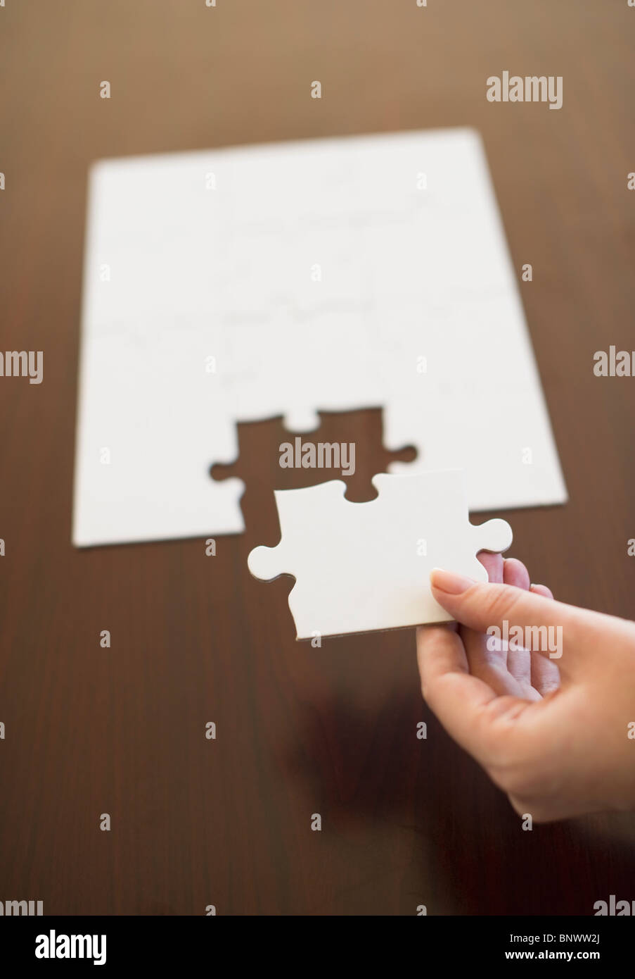 Hand putting last puzzle piece in puzzle Stock Photo - Alamy