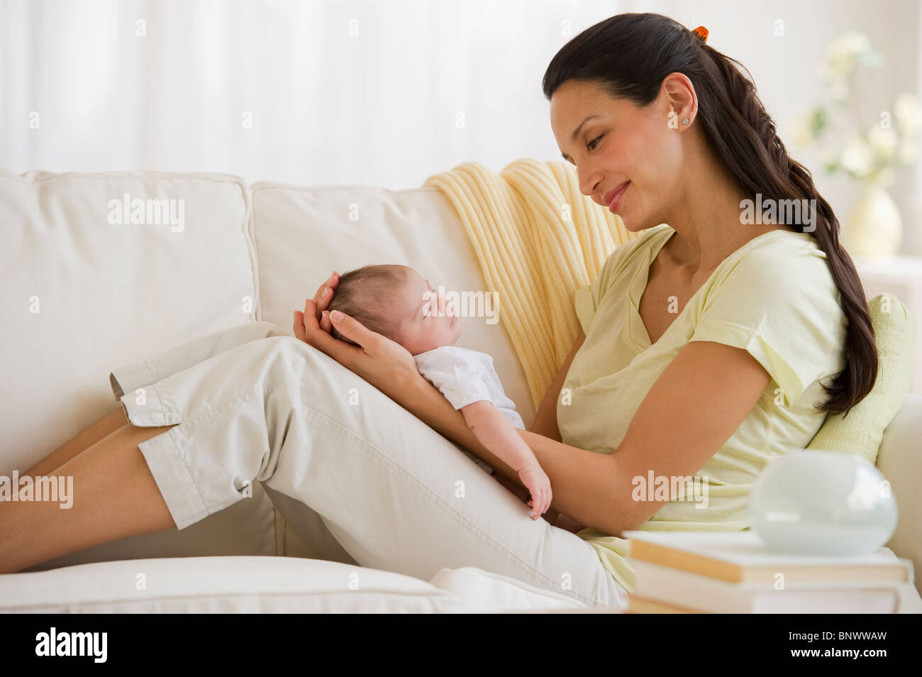 Mother sitting on couch with her baby Stock Photo - Alamy