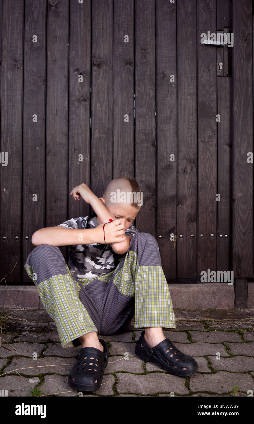 Young injured boy with bleeding arm sitting down outside Stock Photo ...