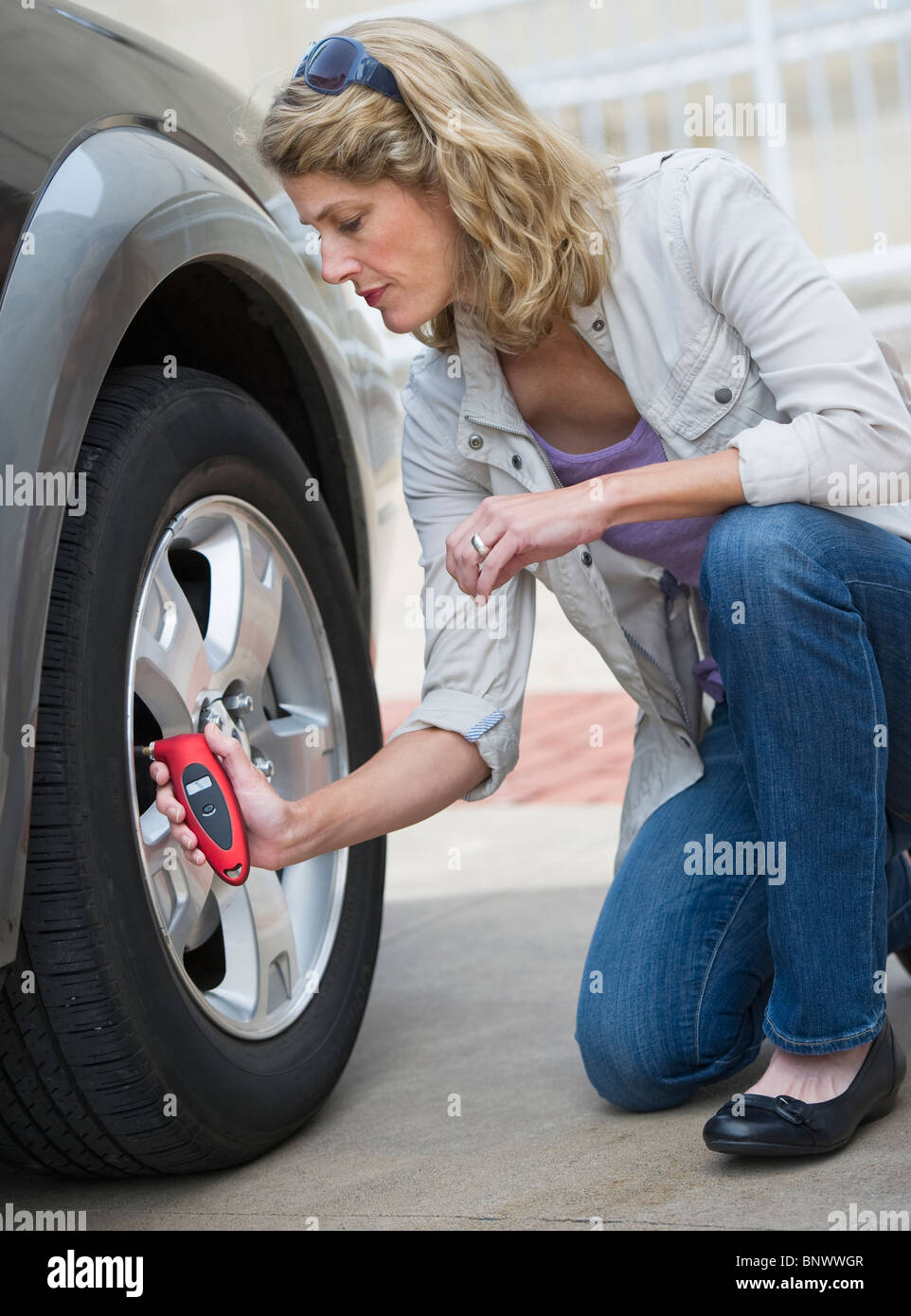Woman using pressure gauge to check tire pressure Stock Photo - Alamy