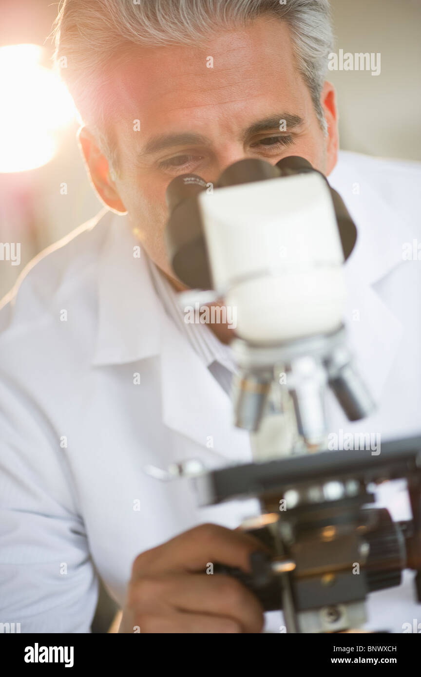 Researcher looking through microscope Stock Photo - Alamy