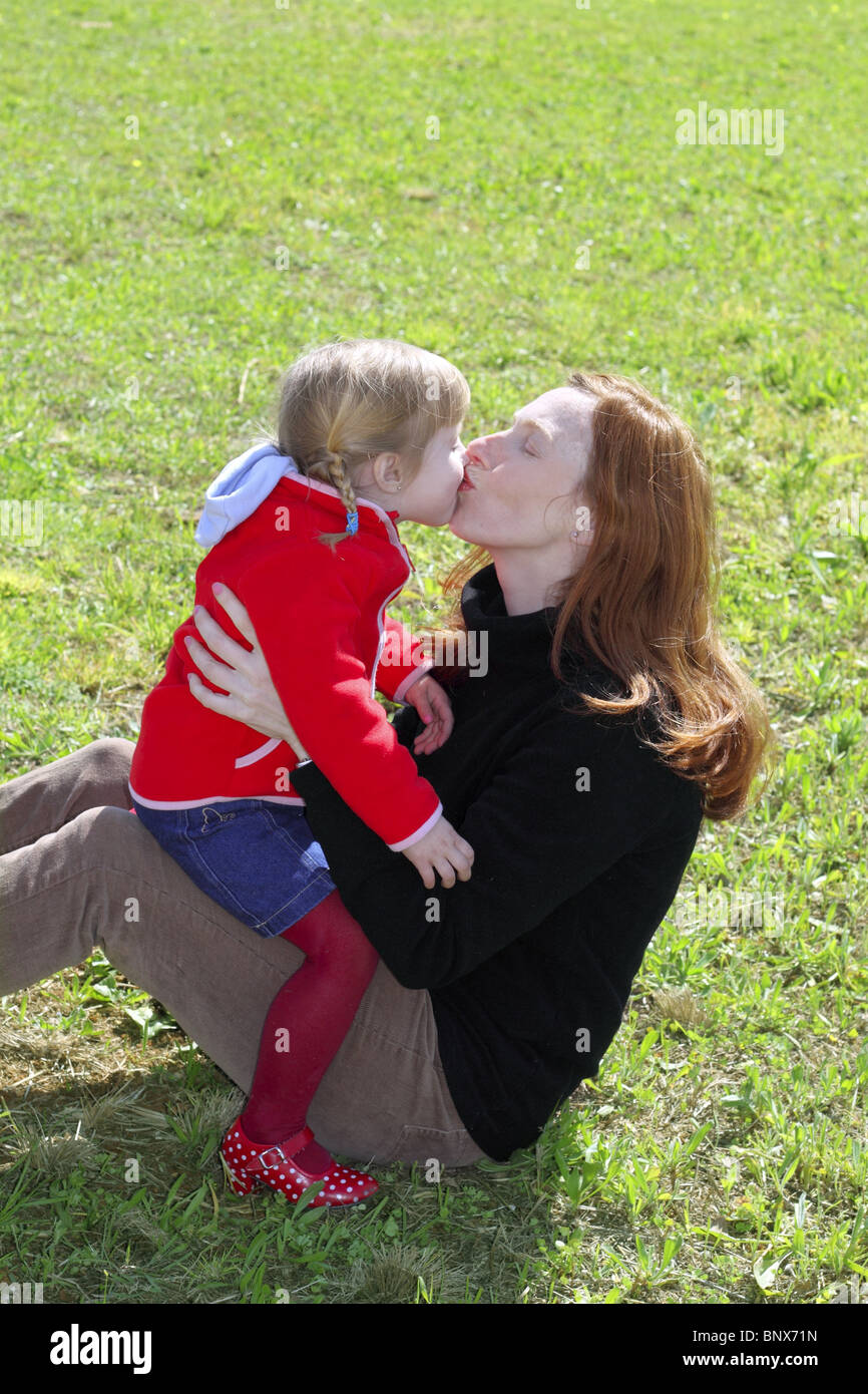 mother and daughter kissing mouth lips hug in winter meadow grass Stock ...