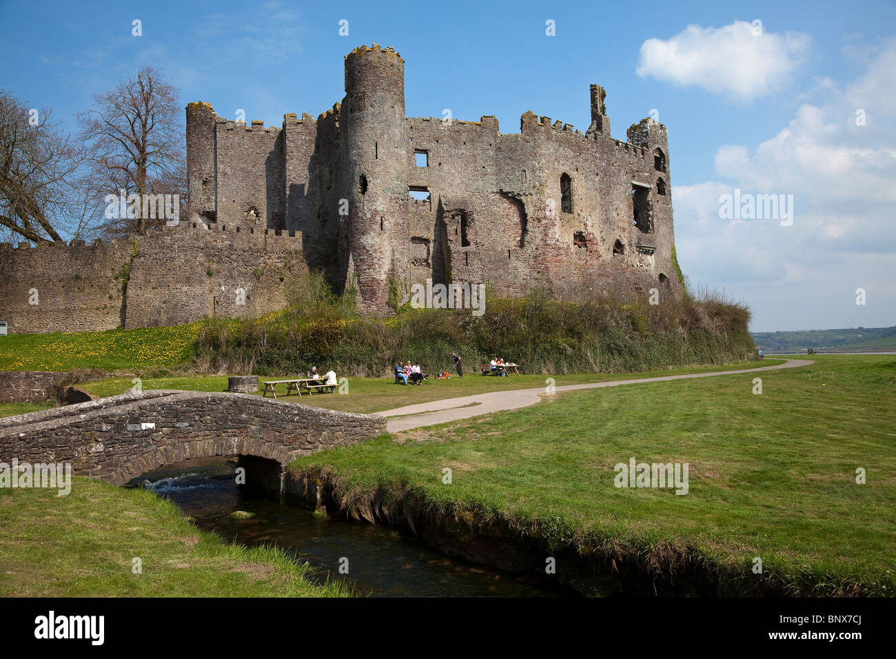 People at picnic benches outside castle ruin Laugharne Wales UK Stock ...