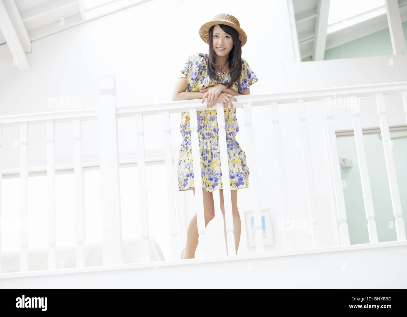 Young woman leaning on railing Stock Photo - Alamy