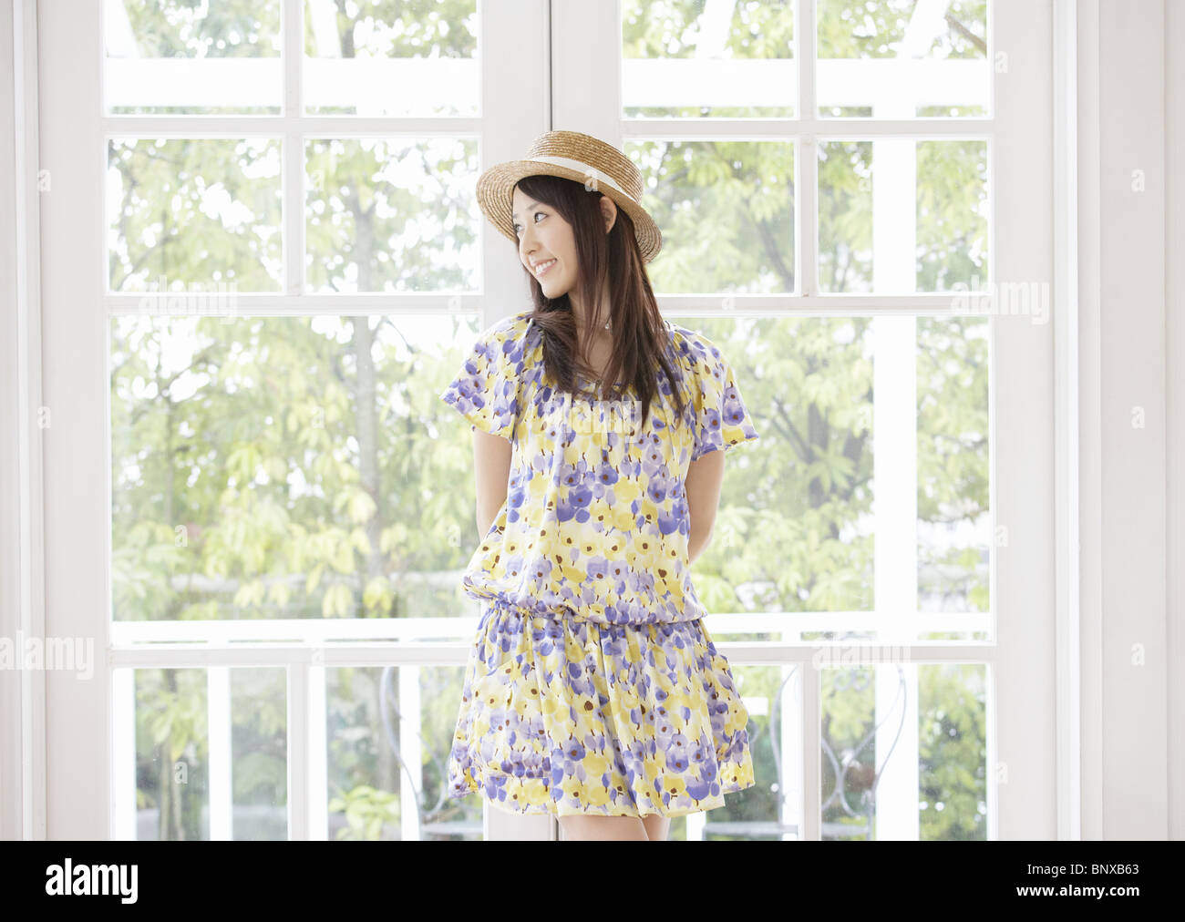 Young woman standing by the window Stock Photo - Alamy