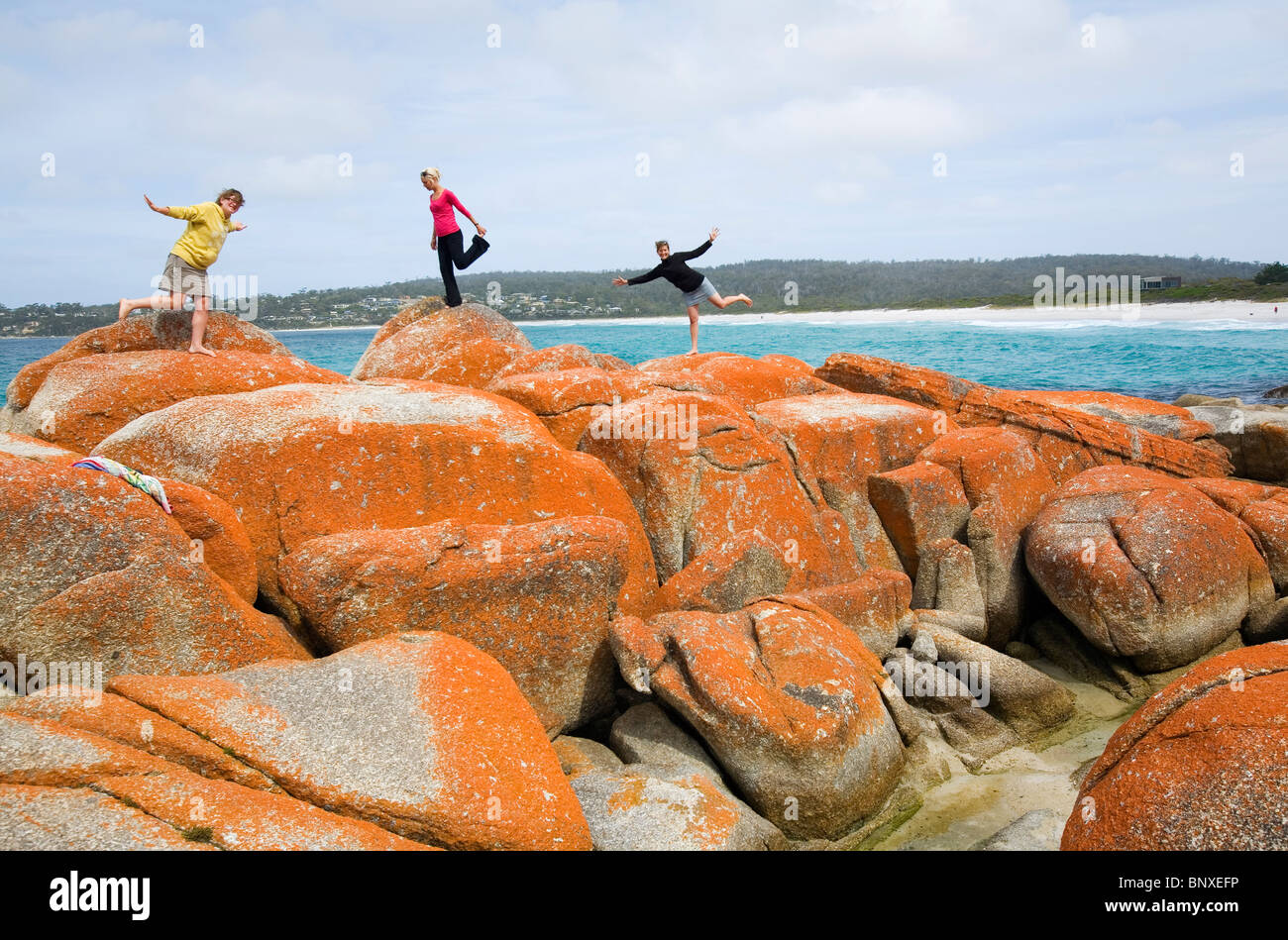 Tourists having fun on the orange lichen rocks of Binnalong Bay. St ...