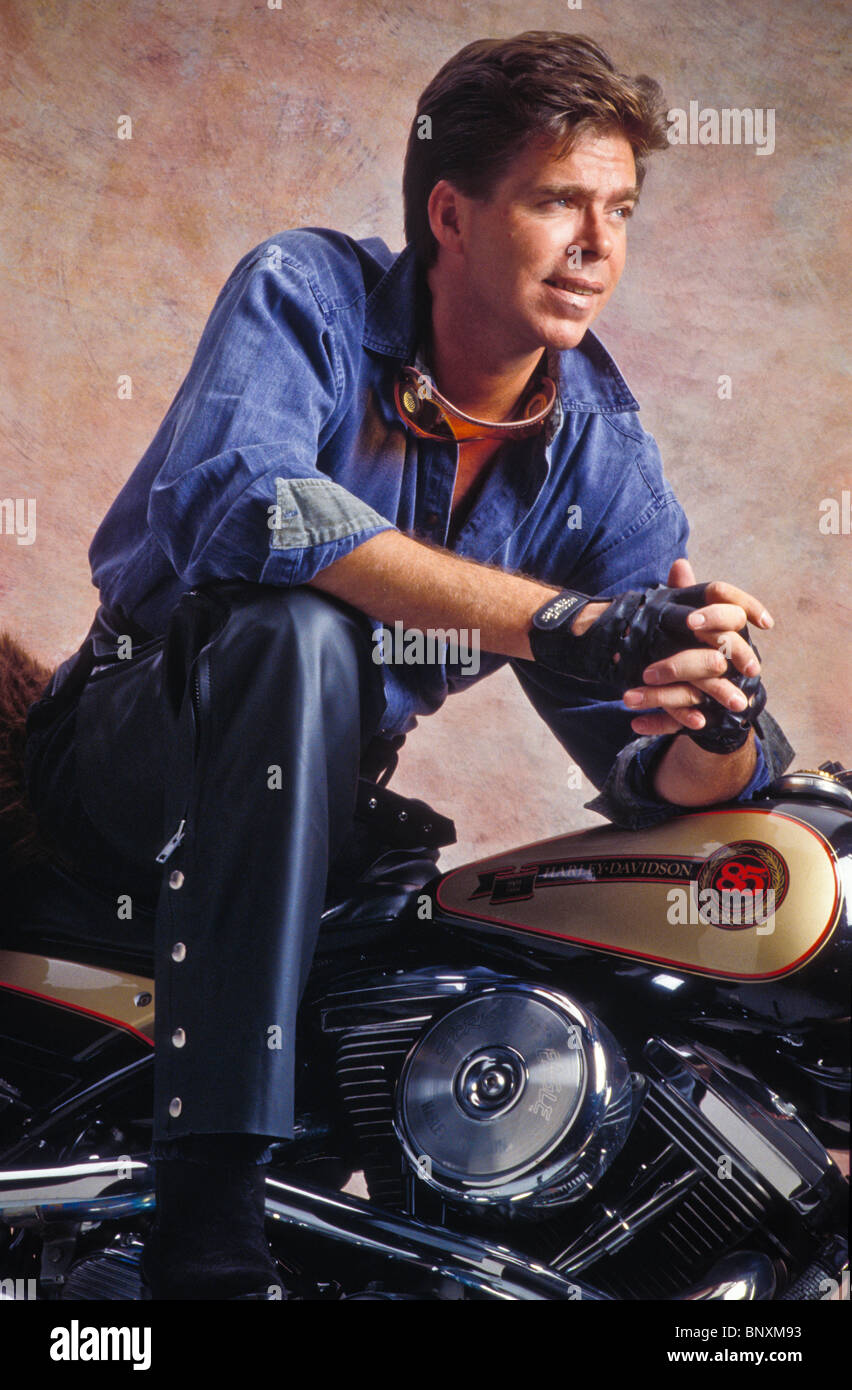 Motorcyclist sitting on bike, smiling Stock Photo - Alamy