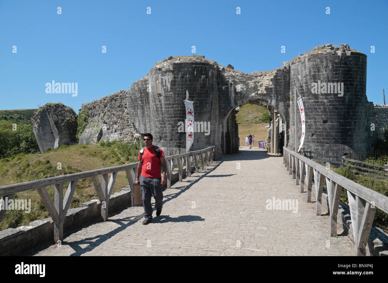 A visitor walking away from the entrance gate to Corfe Castle, Dorset ...