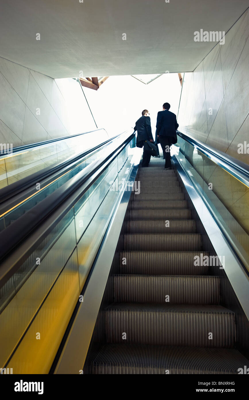Businessmen riding escalator, rear view Stock Photo - Alamy