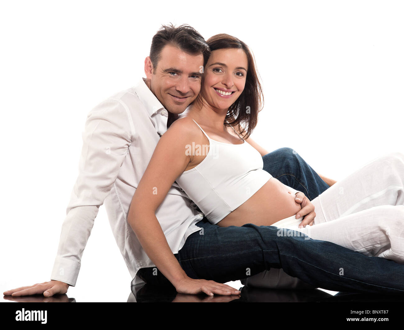 Couple expecting baby sitting complicity isolated studio on white ...
