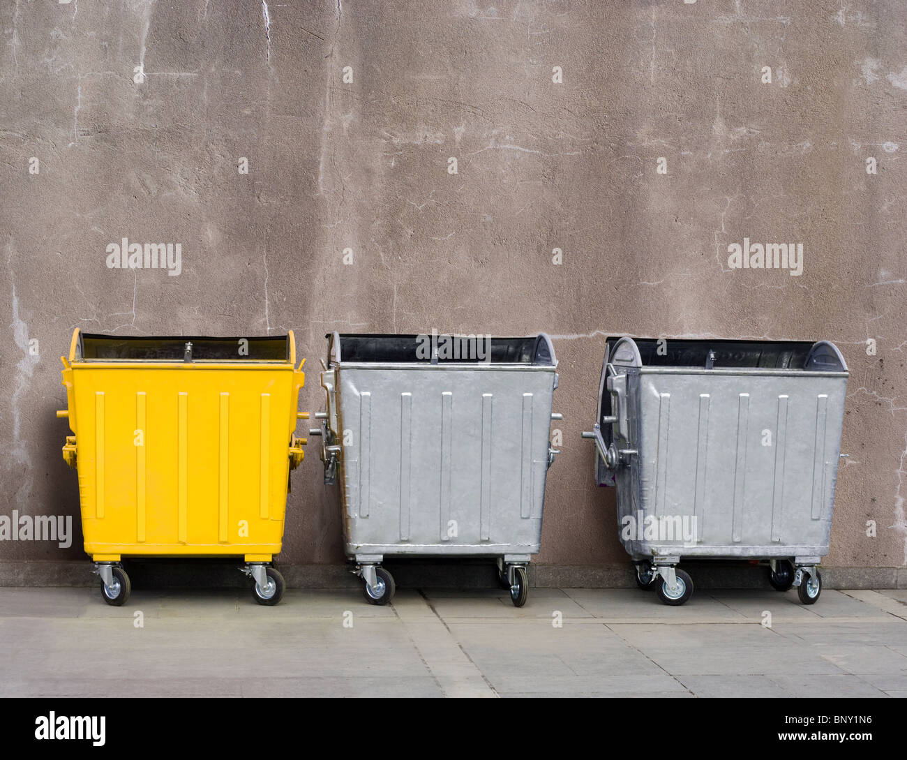 one yellow and two zinc garbage tanks near the wall Stock Photo - Alamy