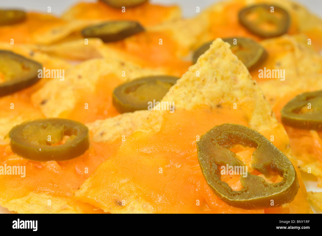 Closeup of nachos with melted cheddar cheese and sliced jalapeno ...