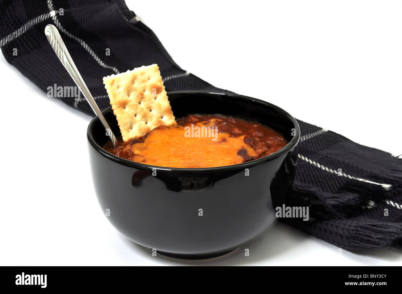 Bowl of chili with melted cheese, cracker, spoon, and scarf. Isolated ...