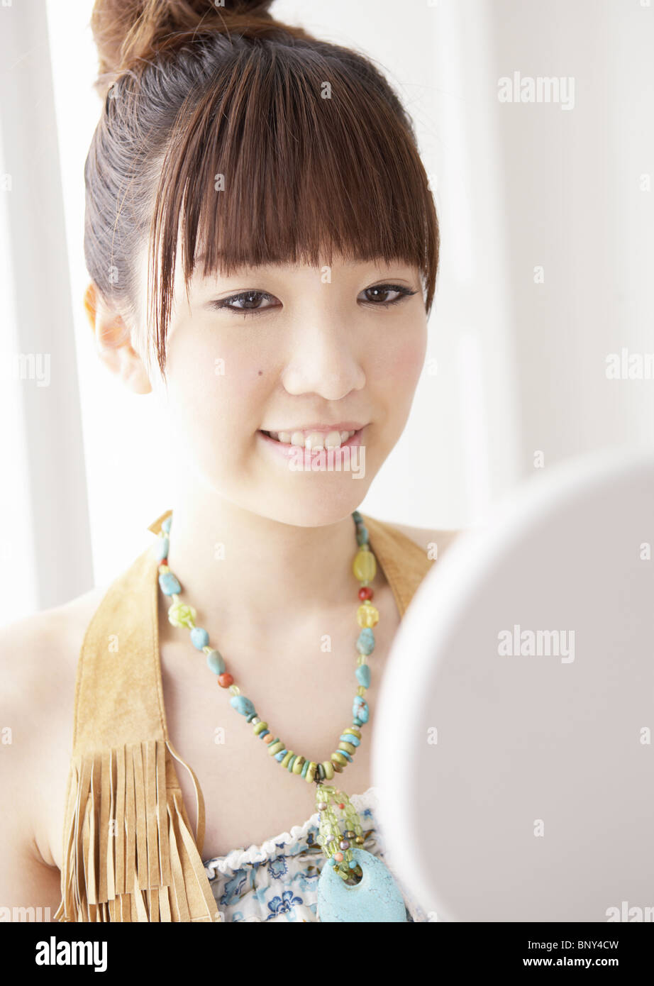Young woman looking in a hand mirror Stock Photo - Alamy