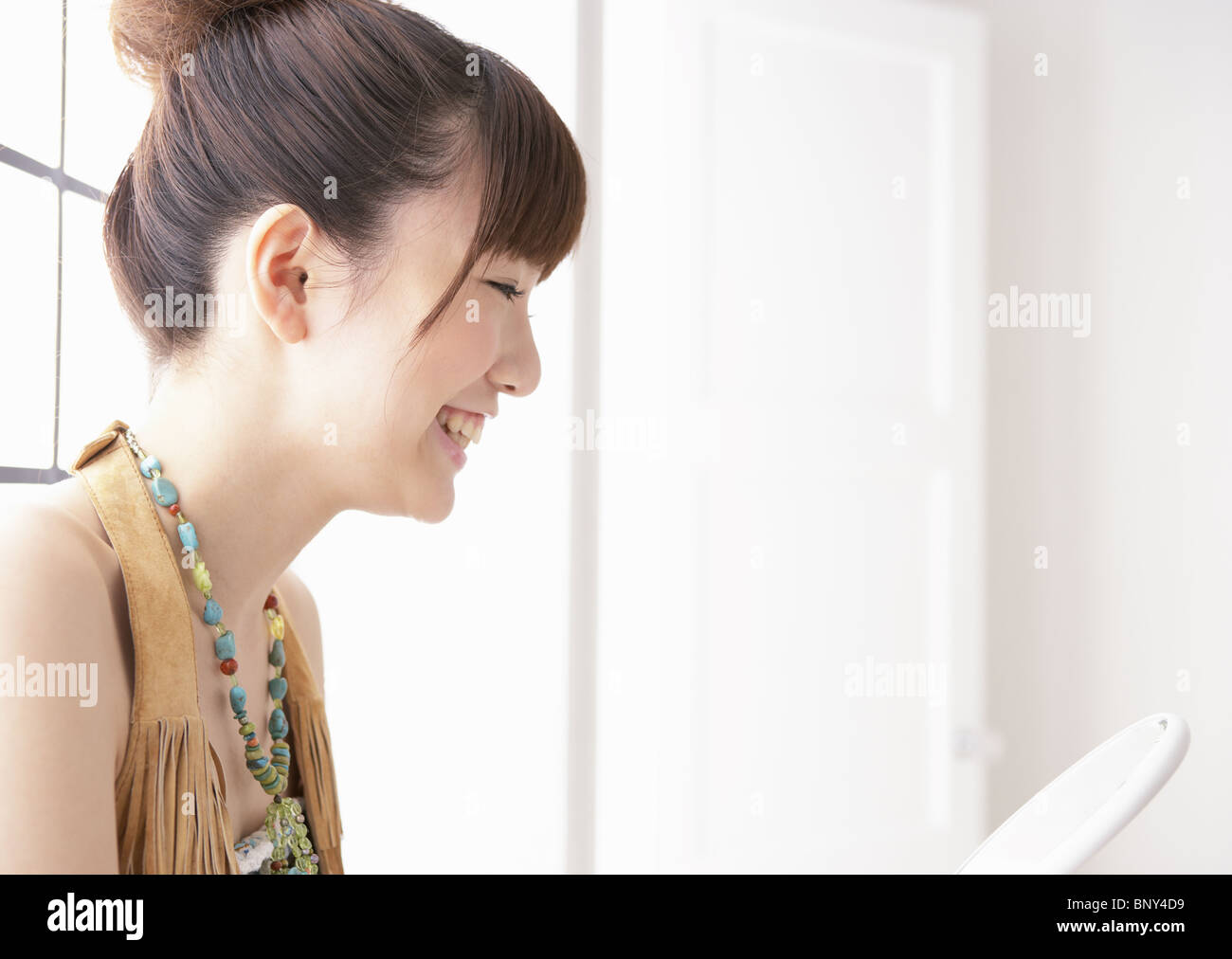 Young woman looking in a hand mirror Stock Photo - Alamy