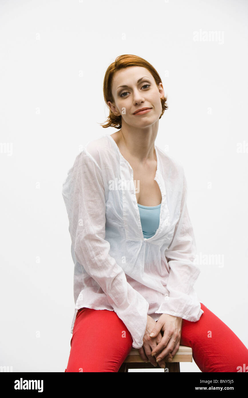 Young woman sitting on stool, portrait Stock Photo - Alamy