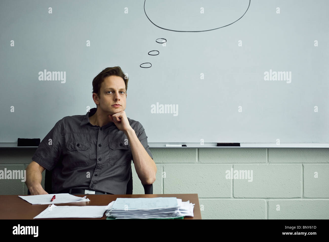 Teacher sitting at desk with stack of papers to grade, portrait Stock ...