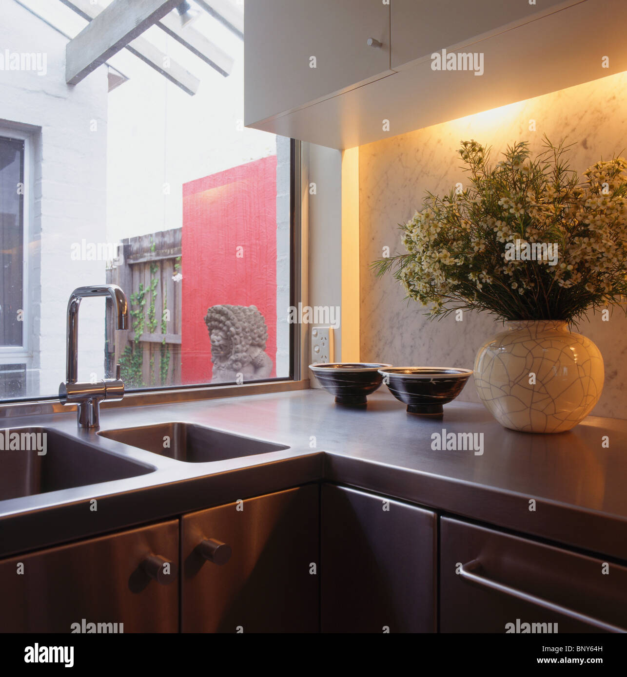 Lighting above vase of flowers on stainless steel worktop in modern ...