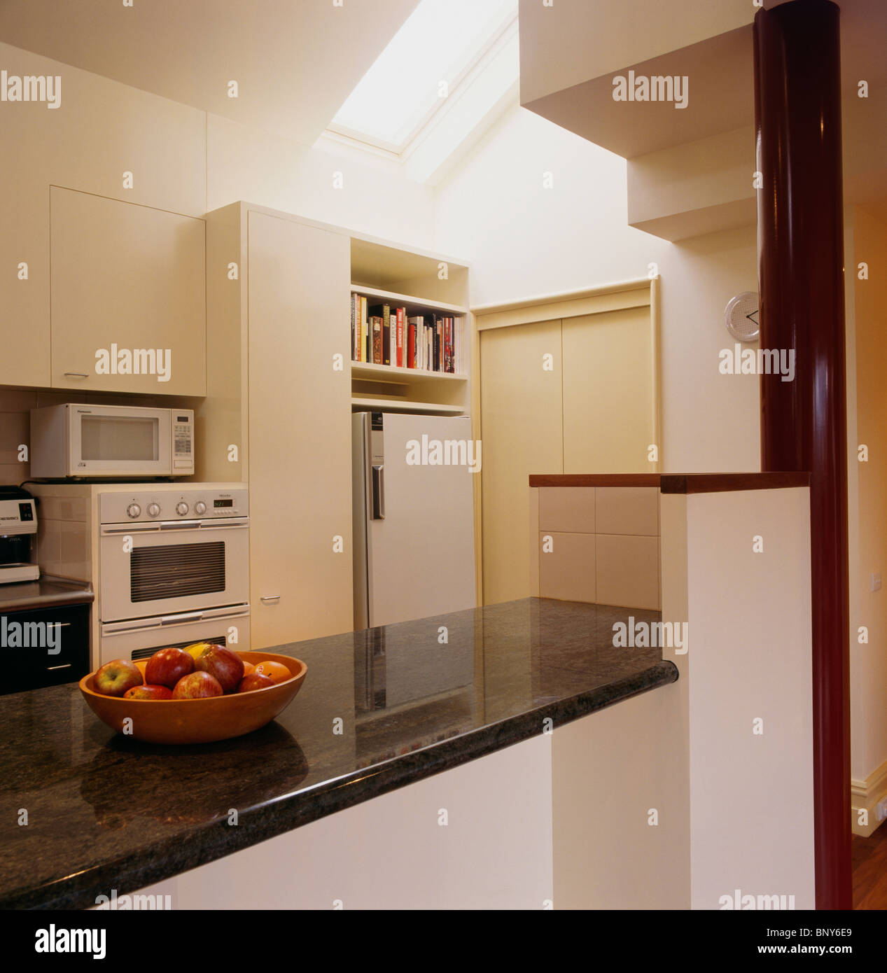 Bowl of fruit on black granite worktop in modern white kitchen ...
