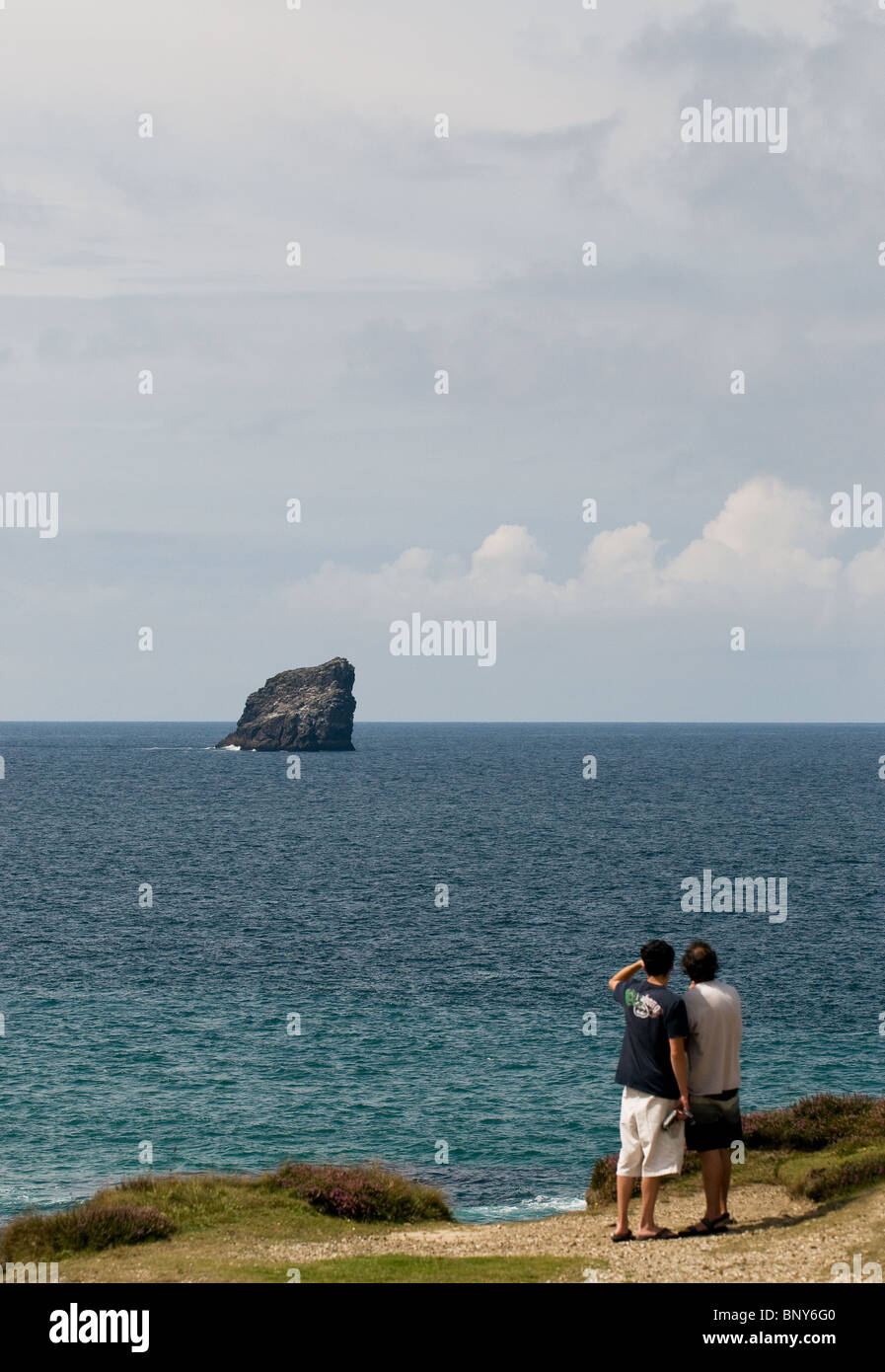 Two holidaymakers looking out to Bawden Rocks at Trevellas Porth in ...
