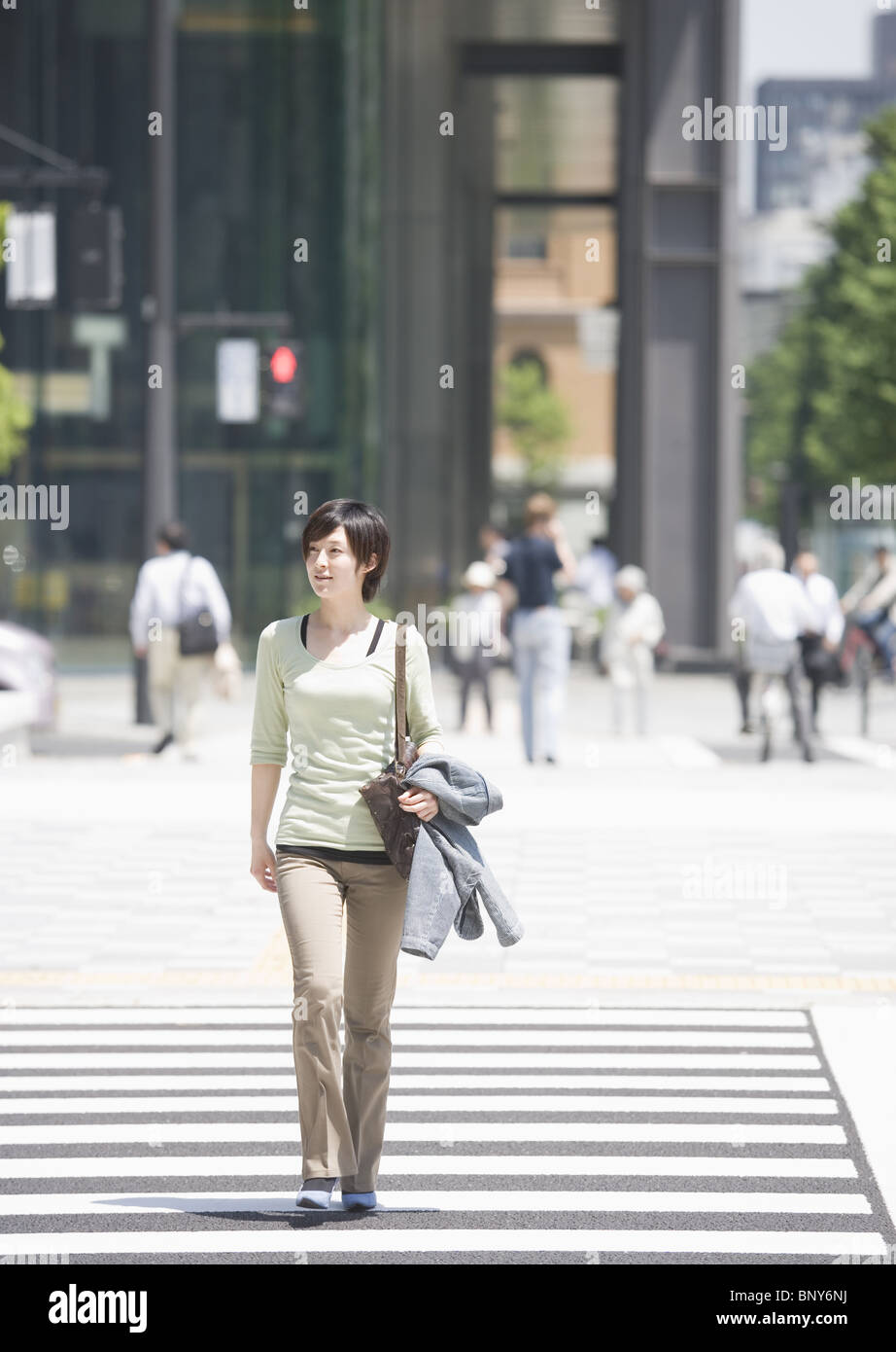 Young woman crossing at crosswalk Stock Photo - Alamy