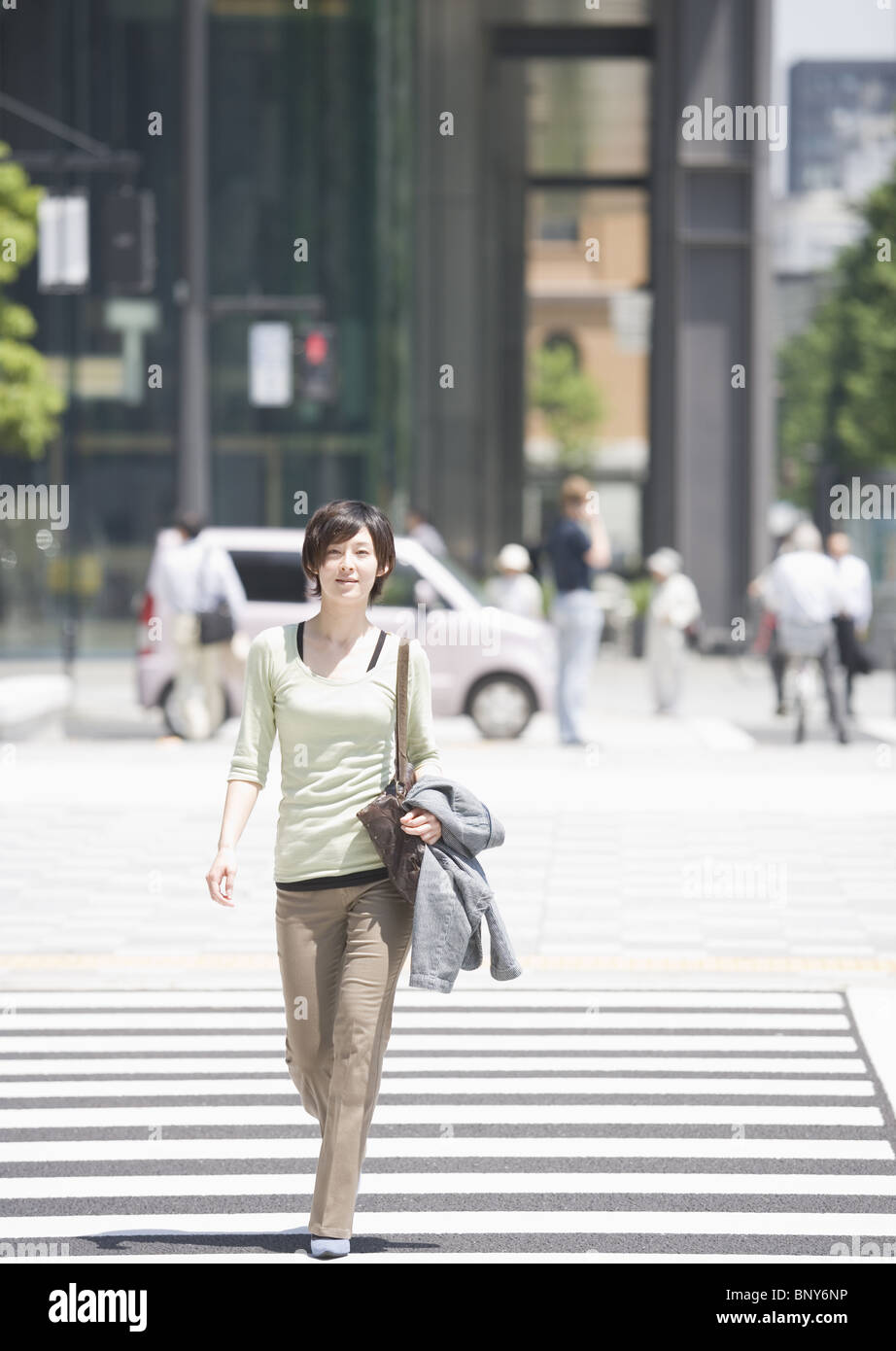 Young woman crossing at crosswalk Stock Photo - Alamy