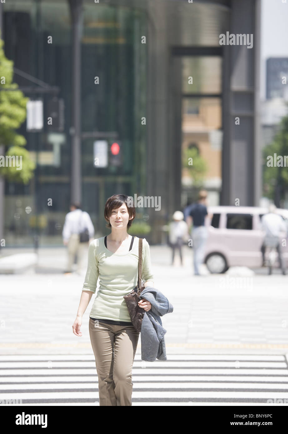 Young woman crossing at crosswalk Stock Photo - Alamy