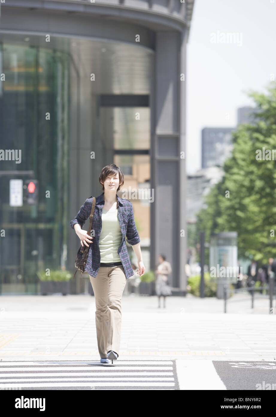 Young woman crossing at crosswalk Stock Photo - Alamy