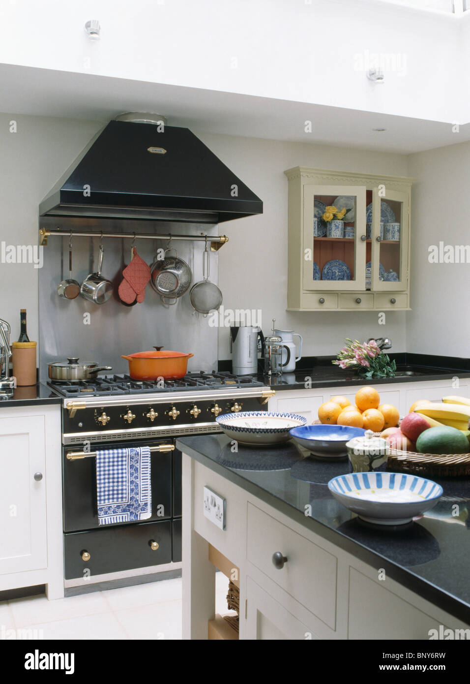 Black extractor and saucepans on rack above range oven in modern ...