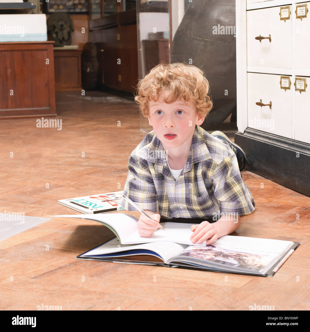 Boy looking up from book and note pad Stock Photo - Alamy