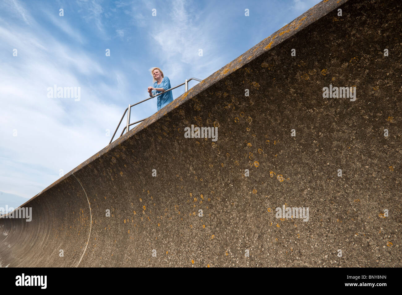 Woman leaning on rail above wall Stock Photo - Alamy