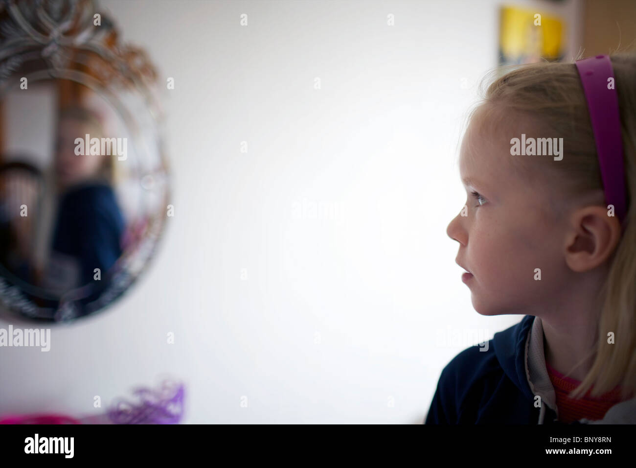 A young girl looks at her reflection in a mirror Stock Photo - Alamy