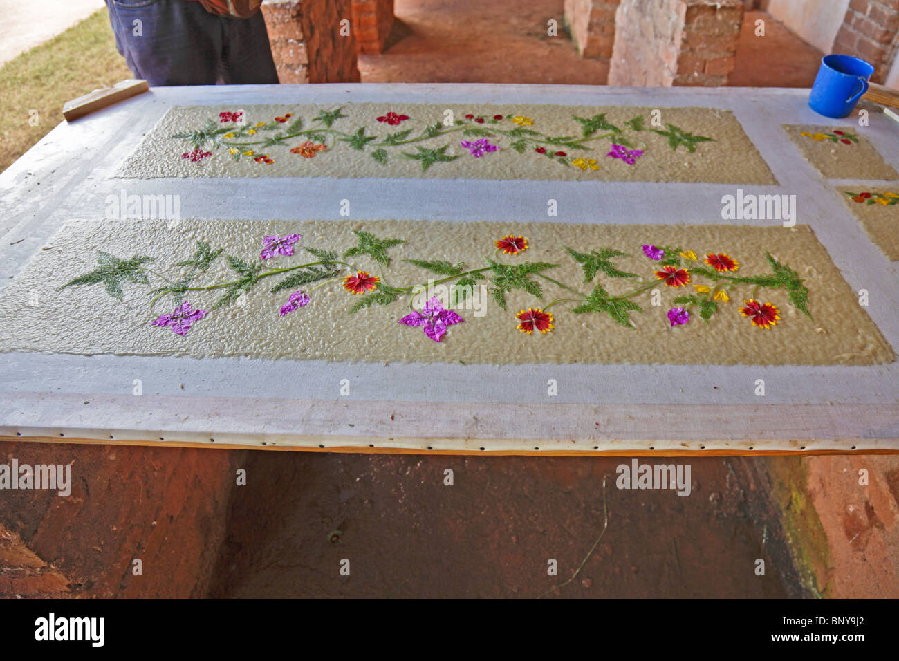 Handmade paper with inlaid petals and leaves out drying on a stretcher ...