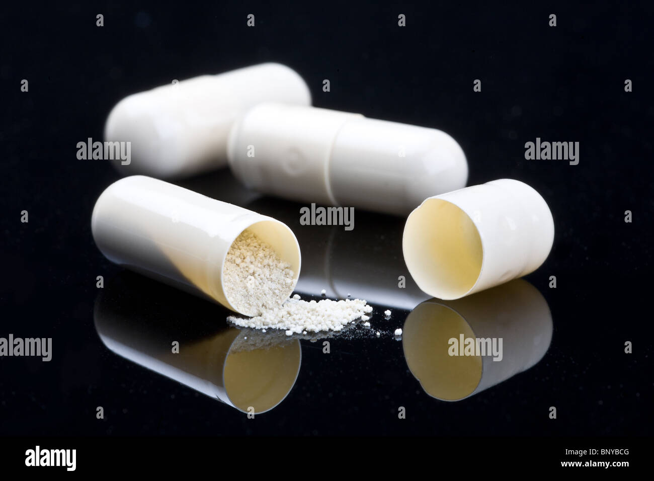 close-up of three white medical capsules , (one opened), isolated on ...