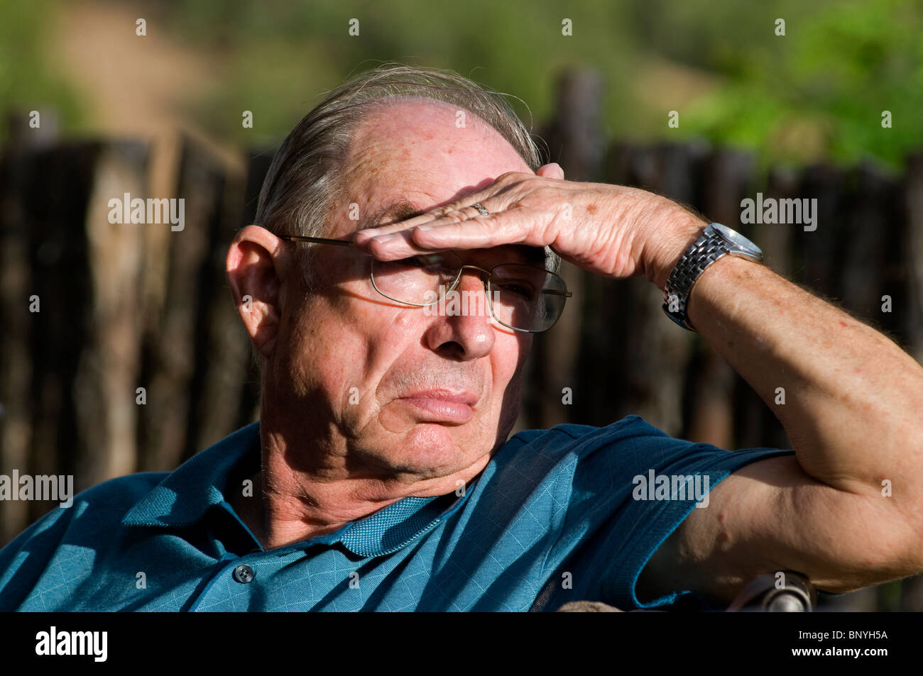 Elderly gentleman sitting with hand shading eyes from sun Stock Photo ...