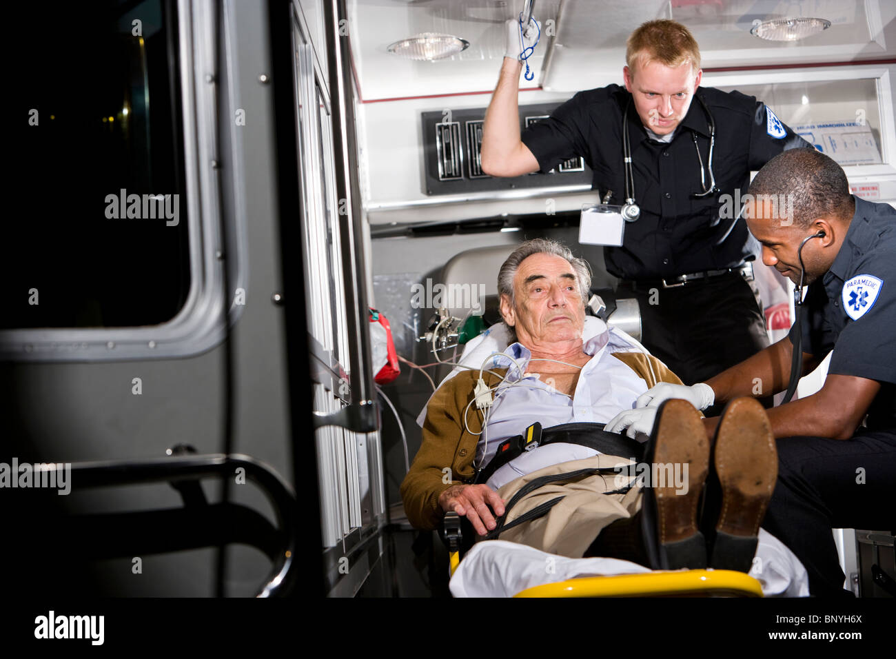 Paramedics caring for elderly patient on stretcher in ambulance Stock ...