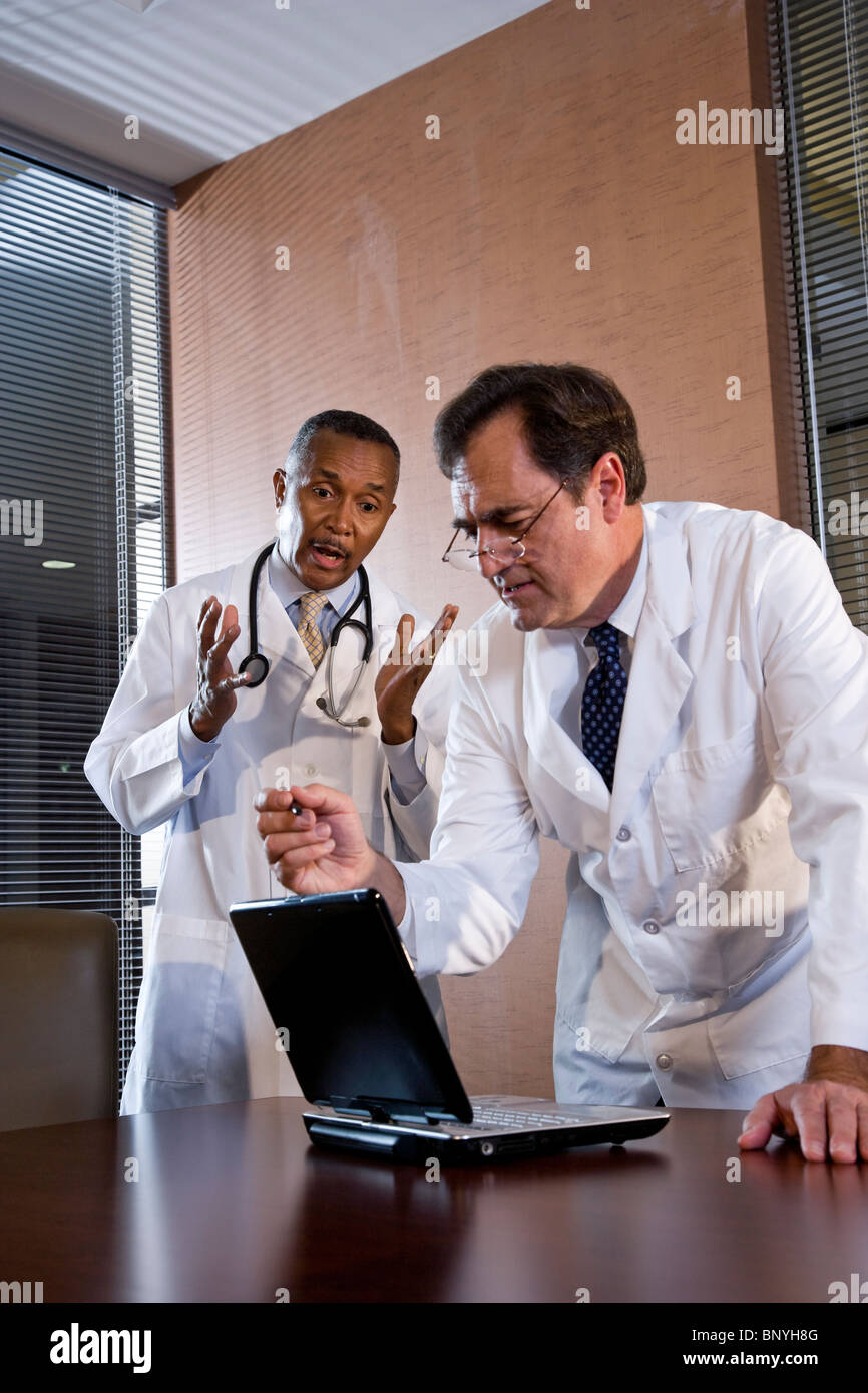 Doctors analyzing and discussing data on laptop computer Stock Photo ...