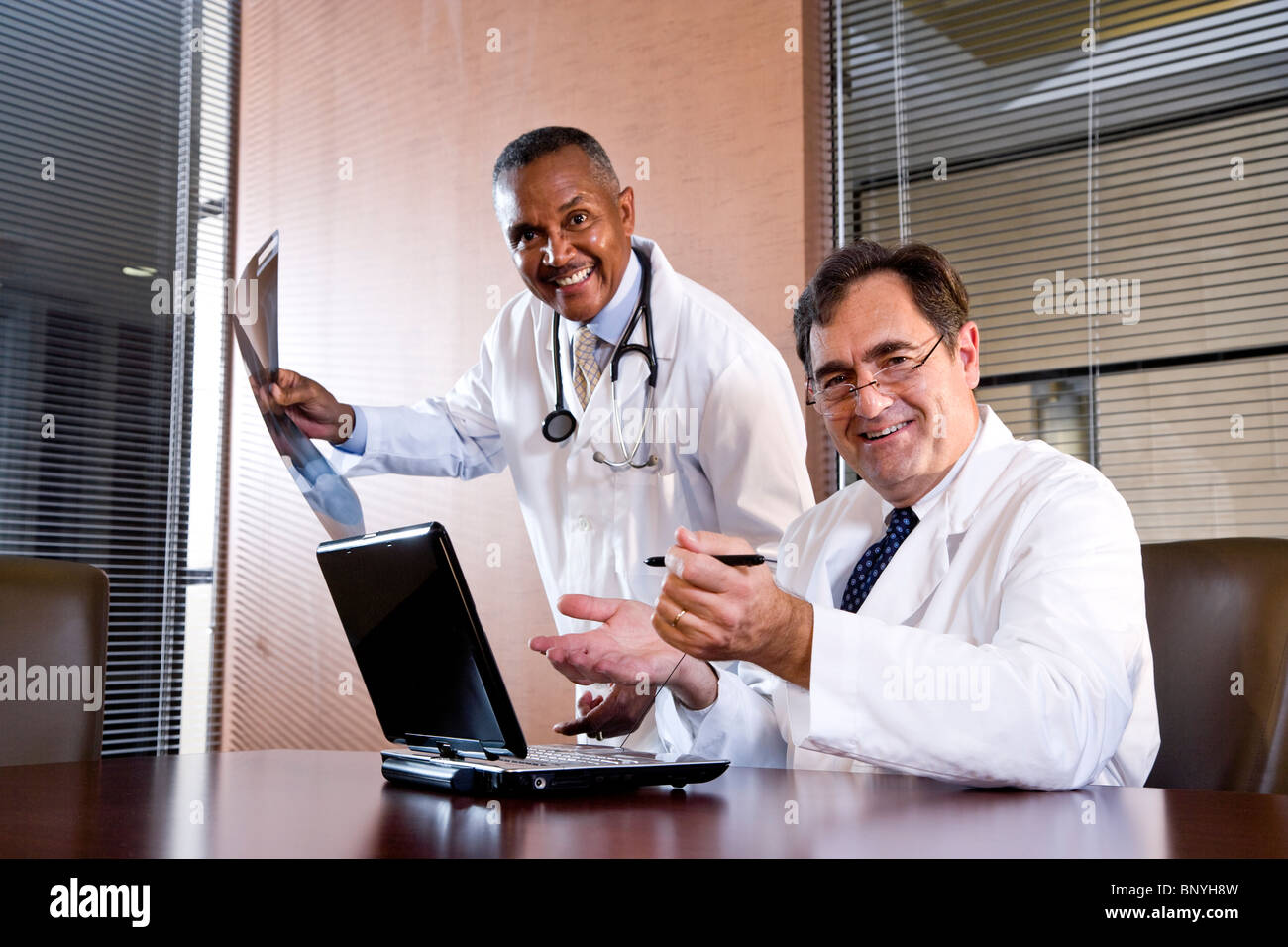 Happy doctors working in an office on laptop Stock Photo - Alamy