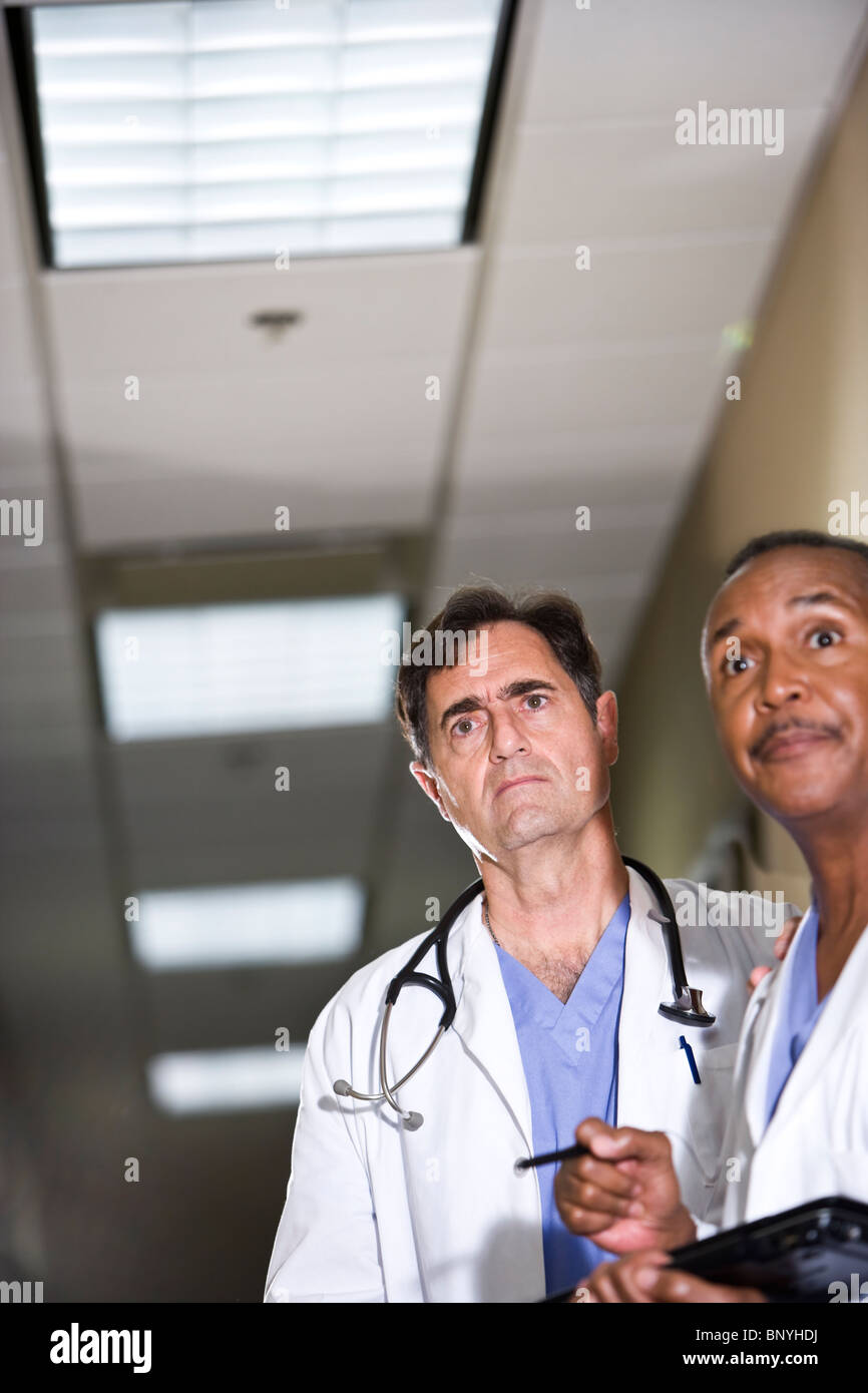 Two doctors looking down hallway Stock Photo - Alamy