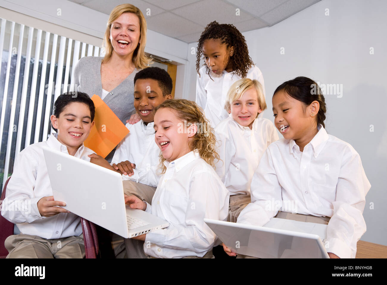 Diverse group of elementary students with teacher in class using ...