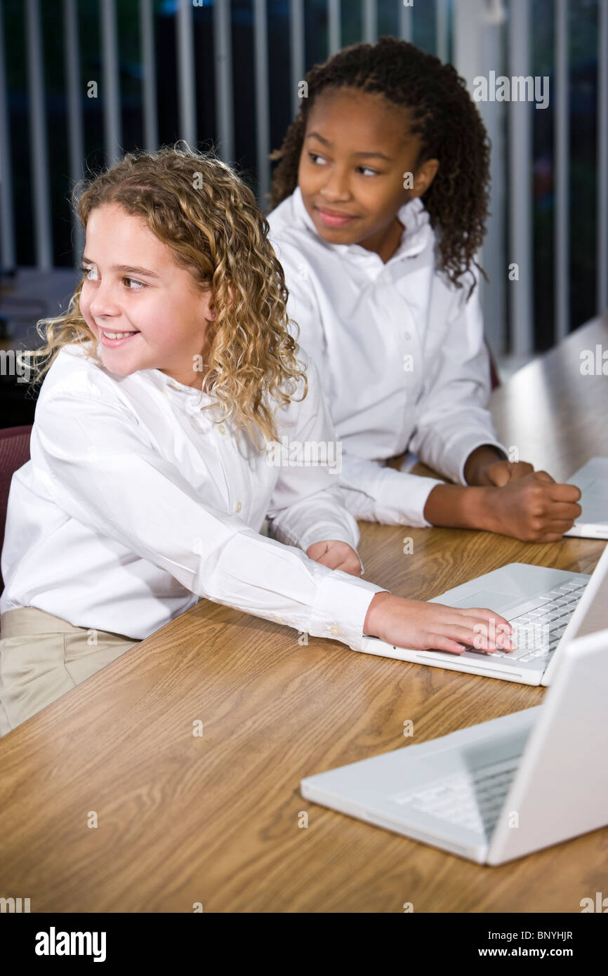 Young multiracial girls using laptop computer in school Stock Photo - Alamy