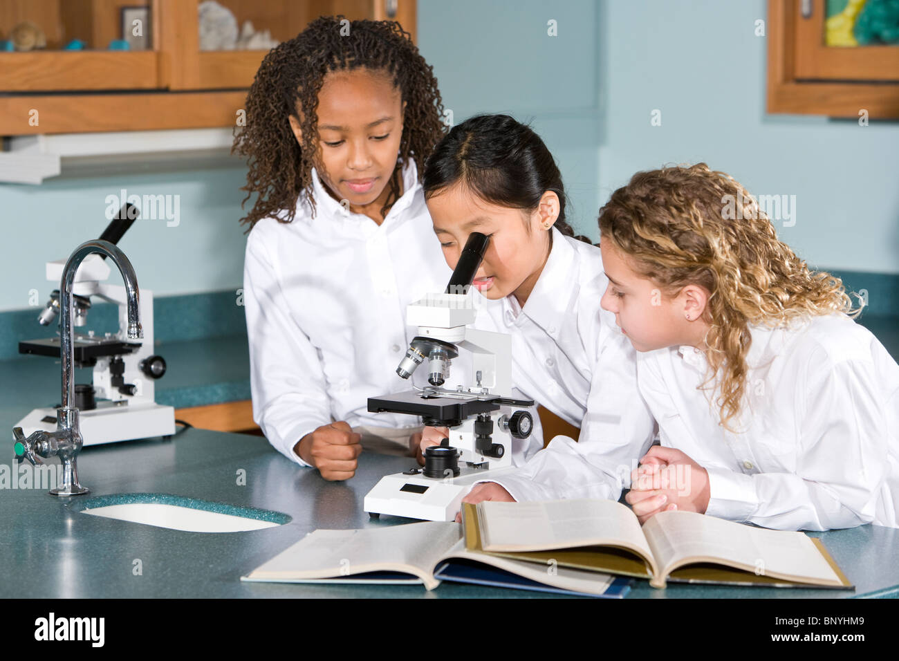 Multi-ethnic elementary school children in science lab using microscope ...