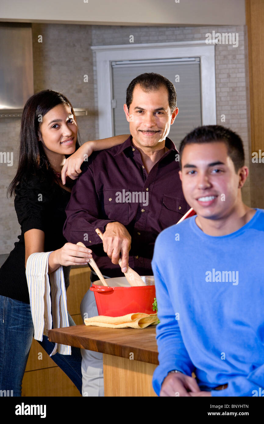 Mature Hispanic man cooking at home in kitchen with teenagers Stock ...