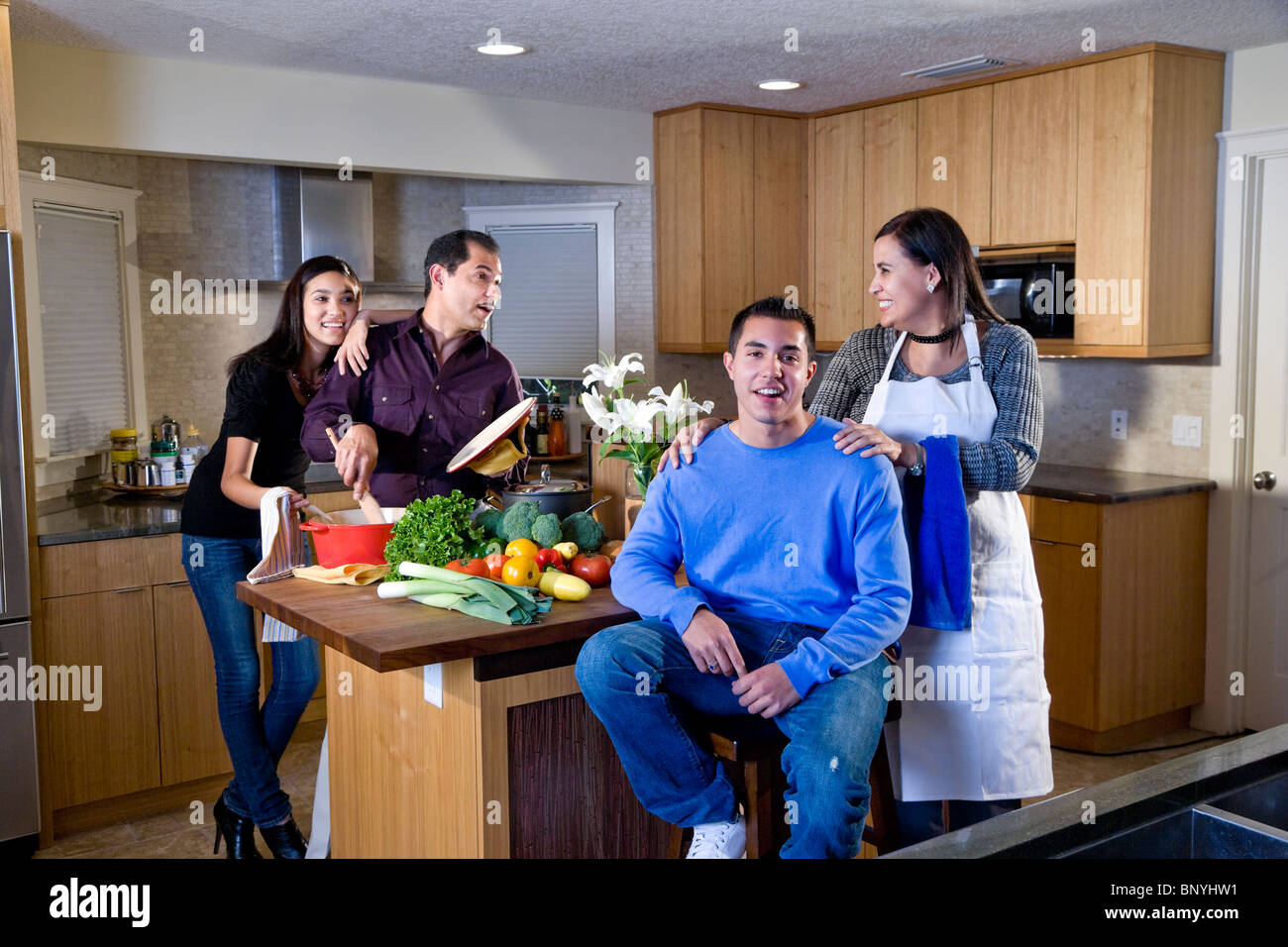 Hispanic family with teenage children cooking together in kitchen Stock ...
