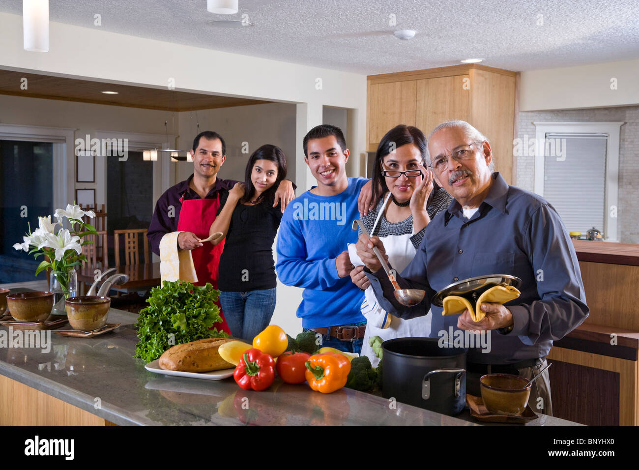 Three generations, Hispanic family cooking together in kitchen at home ...